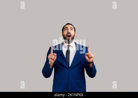 Surprised and amazed man looking at promotion, pointing fingers left at ...