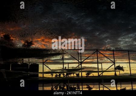 Silhouette of a sport court wet from the rain against dramatic sunset ...