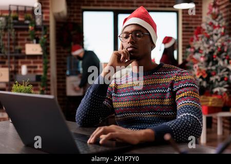 Workplace with laptop, Christmas gifts and decorations near pink wall ...
