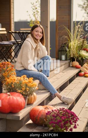 Happy lady seated on the veranda of her cottage Stock Photo - Alamy