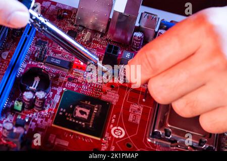A man soldering a motherboard. Repair and maintenance of desktop ...