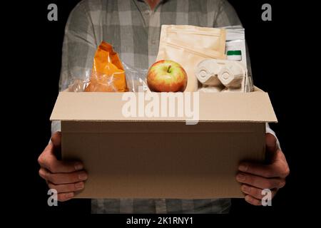 Unrecognizable man holding donation carton box with different products ...
