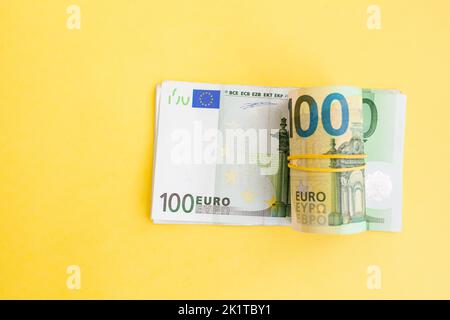 A roll of euro banknotes with a yellow elastic band in a small trolley ...