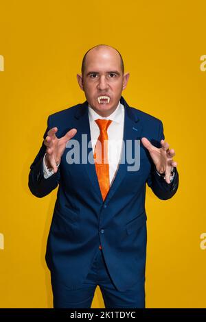 Man in scary vampire costume with fangs posing on orange background ...