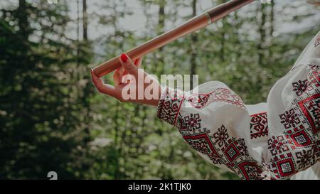 Young woman playing on woodwind wooden flute - ukrainian telenka or ...