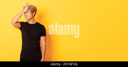 Upset and troubled asian guy snap forehead forgetful, standing over ...