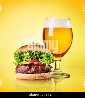 Beer glass and hamburger over color background Stock Photo - Alamy