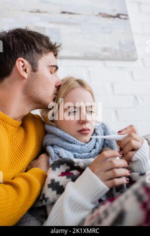 caring man hugging sick blonde woman with digital thermometer,stock ...