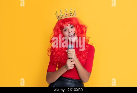 positive child in crown with microphone and party balloon on yellow ...