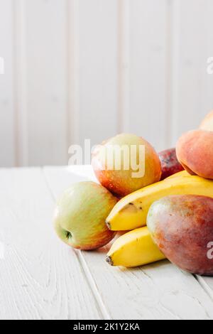 Fresh and ripes fruits - banana, mango, peach and apples on the table ...