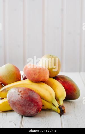 Fresh and ripes fruits - banana, mango, peach and apples on the table ...