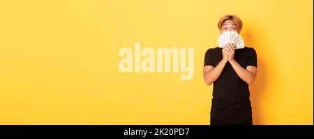 Excited lucky blond asian guy rejoicing from winning cash, holding ...