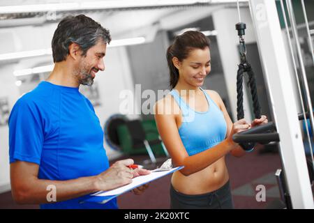Personal Trainer Takes Notes While Young Woman Resting In Gym Stock ...