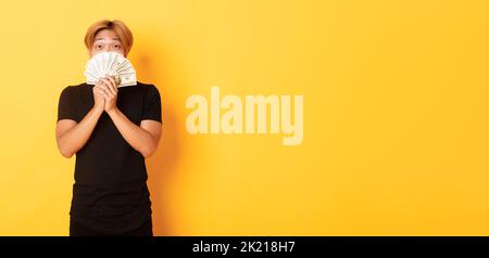 Excited lucky blond asian guy rejoicing from winning cash, holding ...