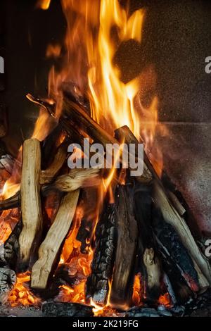 Wood logs burning during a dark night, producing orange flames and ...