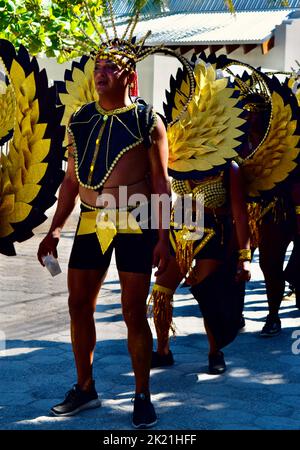 A Belizean man wearing a shiny, winged, black and yellow costume ...