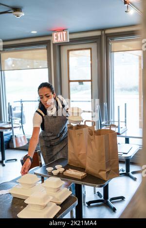 Female business owner bagging takeout orders in cafe Stock Photo - Alamy