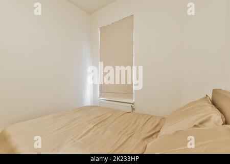 Comfortable bed with blanket and pillows located near closet and ...