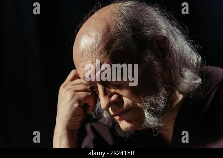 pensive medieval philosopher thinking with bowed head isolated on black ...