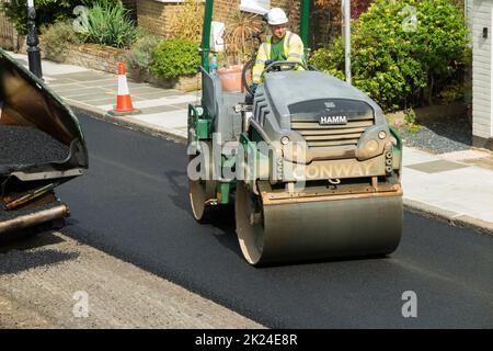 Road roller smoothing hot tarmac that has been laid while resurfacing a ...