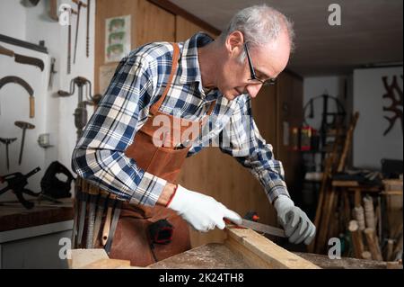 Carpenter filing a plank of wood in his Workshop. High quality ...