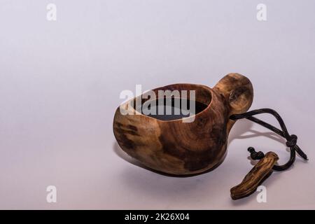 carved wooden cup named kuksa with a fresh coffee on a gray background ...
