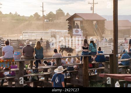 Spectators sitting on wooden benches enjoy the bull riding event at the ...