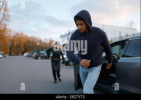 Woman cop running after hooded car thief Stock Photo - Alamy