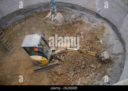 Small excavator is digging in a pit Stock Photo - Alamy