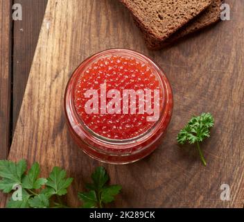 full glass jar with red caviar on a brown wooden table, top view Stock ...