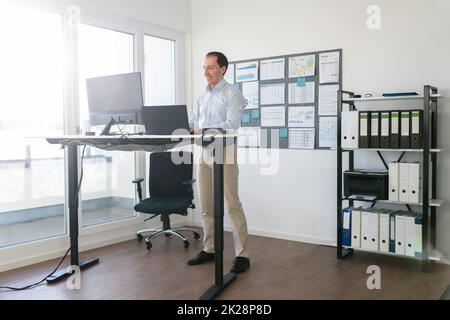 Man Using Adjustable Height Standing Desk In Office For Good Posture ...