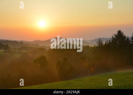 The sun rises over a misty landscape as people dance and move at ...