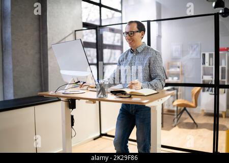 Man Using Adjustable Height Standing Desk In Office For Good Posture ...