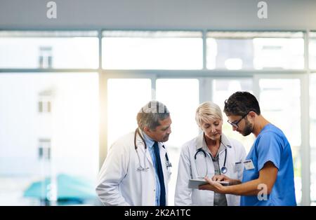 Smart doctors use smart apps. Shot of a team of doctors using a digital ...