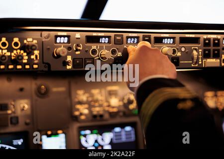 Pilot aviator fixing altitude and longitude level on dashboard in plane ...