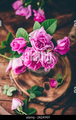 Bunch of small pink Roses in a glass vase over a wooden table Stock ...