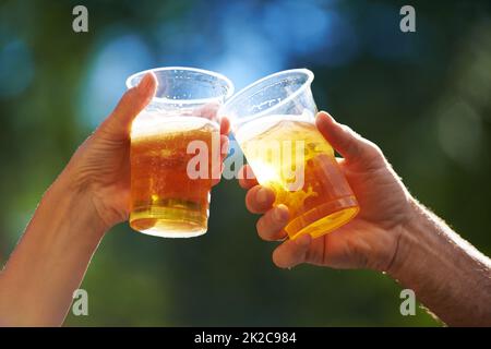 Enjoying a cold one. Cropped view of two people saying cheers with ...