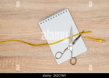 Scissors cutting data cable over a blank spiral notebook. Concept of ...