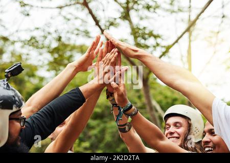 Lets do it. Cropped shot of a group of friends high-fiving at an ...