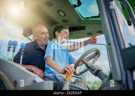 Little boy driving tractor. Son helps father to repair tractor. Involve ...