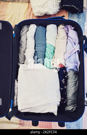 All packed for that vacation. High angle shot of a suitcase packed with ...