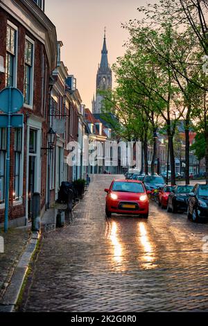Delft cobblestone street with car in the rain with Nieuwe Kerk church ...