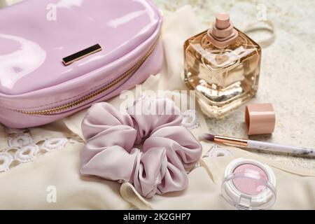 Silk scrunchy and different female accessories on light background ...