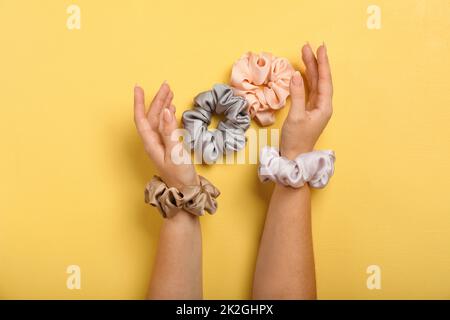 Female hands with different silk scrunchies on yellow background Stock ...