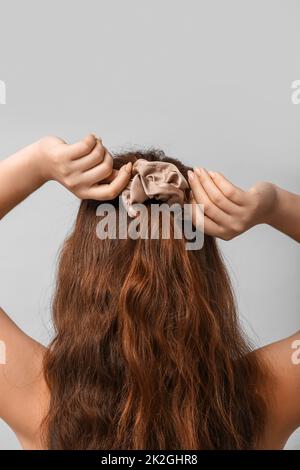 Woman adjusting silk scrunchy on light background, closeup Stock Photo ...