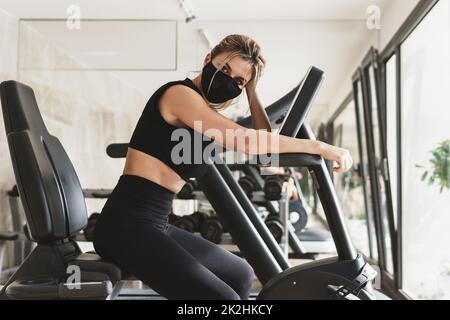 Young athletic woman wearing a prevention face mask during her fitness ...