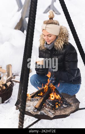 Beautiful woman warming up by the fire pit during cold winter day Stock ...