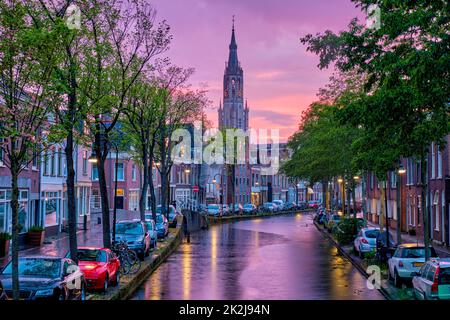 Canal with parked along cars in Delft town in evening dusk after rain ...