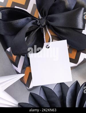 Wrapped present with a white bow and square paper gift tag on a white ...