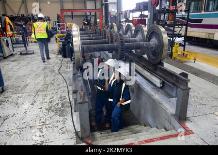 Transit engineers inspecting axles in maintenance facility Stock Photo ...